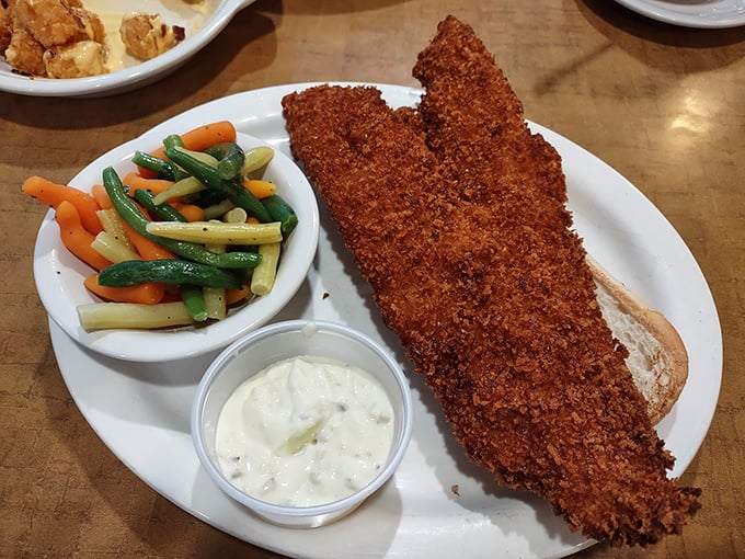 The fish sandwich that launched a thousand return visits, perfectly golden and served with a rainbow of vegetables for those who appreciate balance.