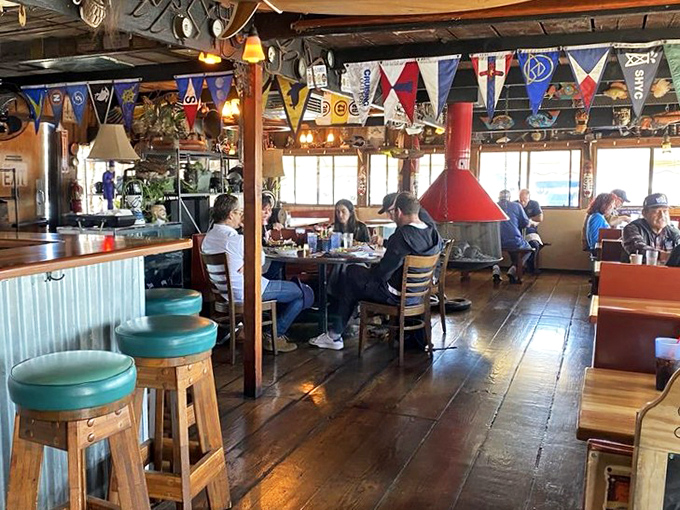 Where nautical flags meet wooden beams and conversation flows as freely as the drinks. The slanted floor reminds you—you're dining on water.