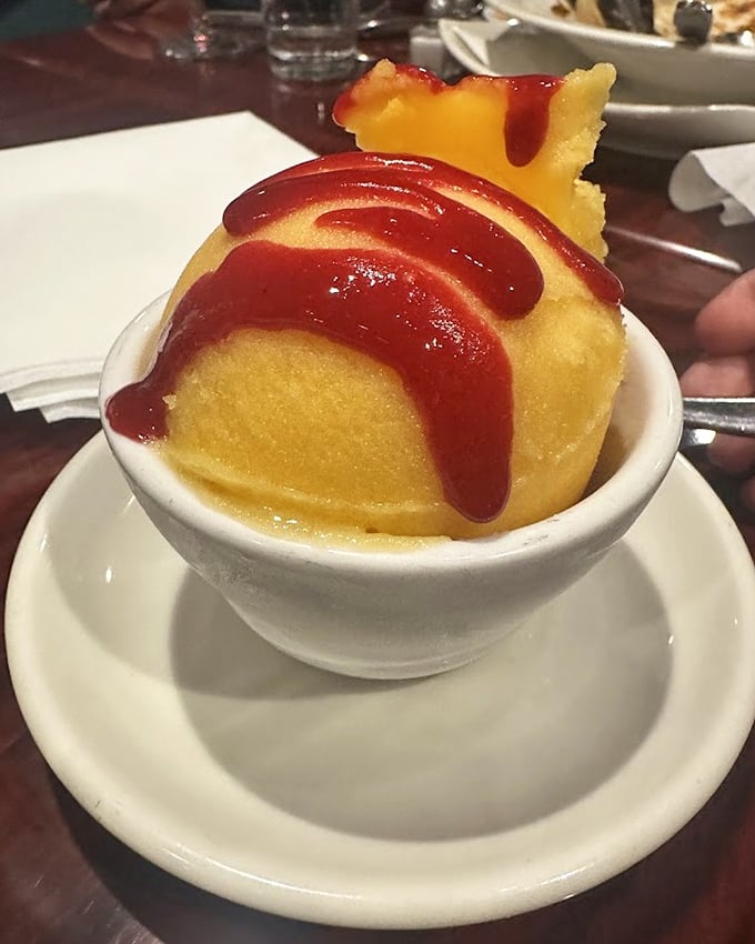 This isn't just mango sorbet—it's summer sunshine in a bowl, drizzled with raspberry sauce and topped with a crisp cookie sail.