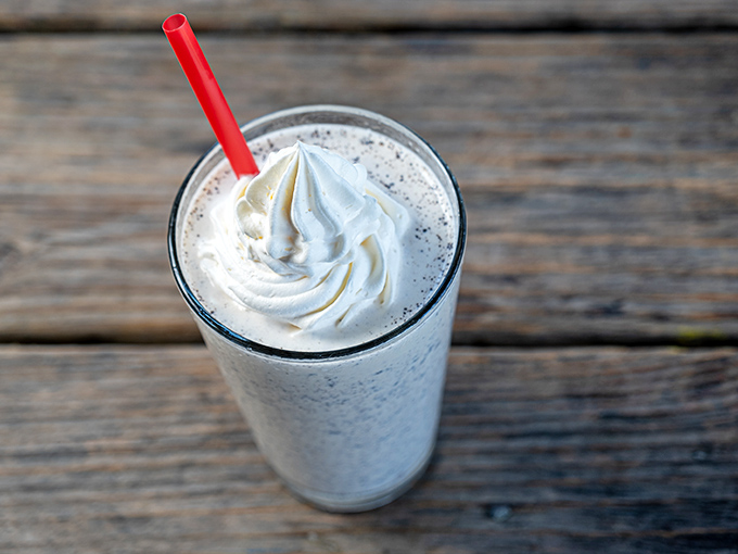 Cloud-like whipped cream atop what must be a milkshake so thick it fights the straw—dessert and beverage having a beautiful identity crisis.