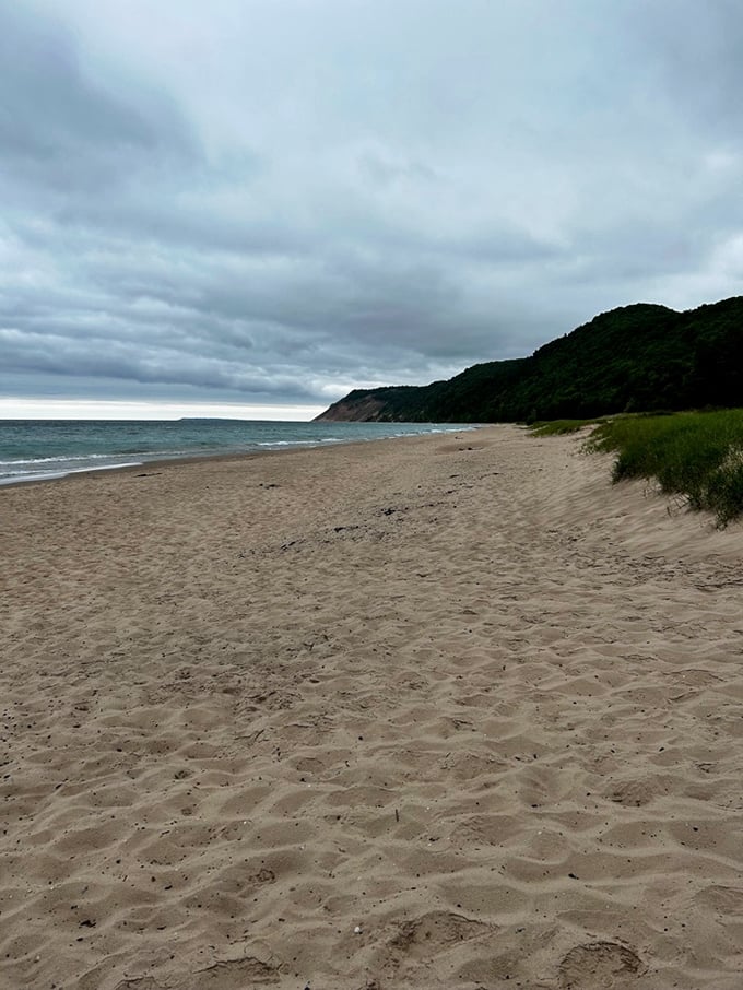 Beach math: fewer footprints equals more serenity. The dune grass stands like nature's velvet rope, protecting this slice of Great Lakes perfection.
