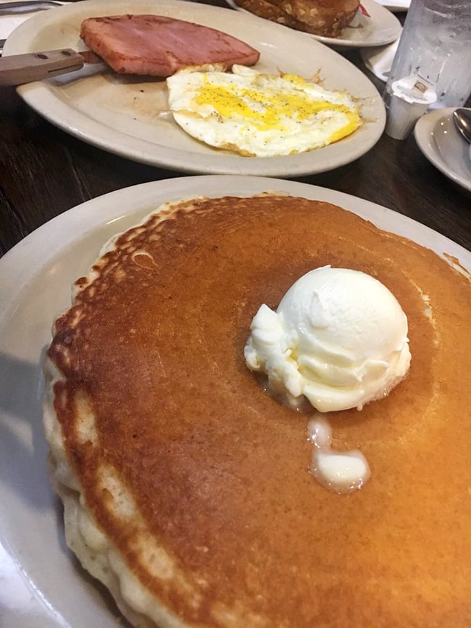 This isn't just a pancake—it's a golden-brown canvas of possibility, topped with a melting scoop of butter that's creating its own little syrup river.