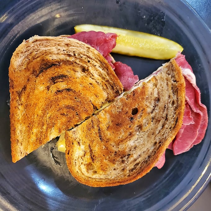 A proper Reuben doesn't need fancy presentation—just perfectly toasted rye, the right ratio of meat to kraut, and a pickle standing guard nearby.