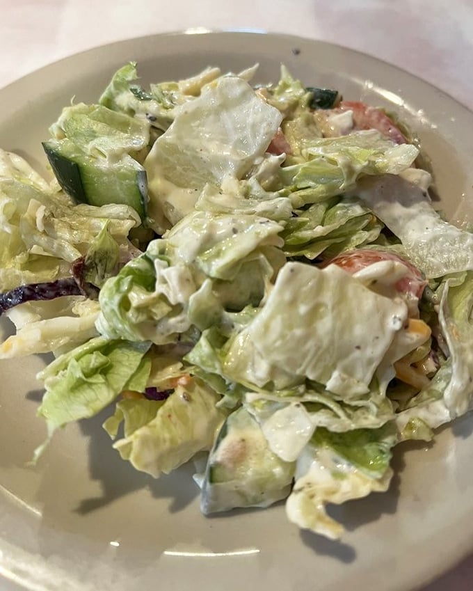 A house salad that didn't get the memo about being a boring obligation—creamy dressing, fresh vegetables, and enough flavor to hold its own.