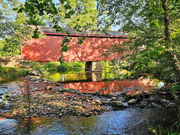 The reflection creates a perfect circle – architecture above, nature below. Water and wood have coexisted here for over a century.