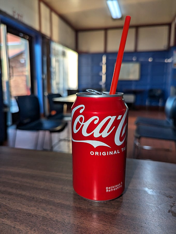 Even the soda comes with no pretense – just a can, a straw, and the promise of fizzy refreshment against that golden batter.