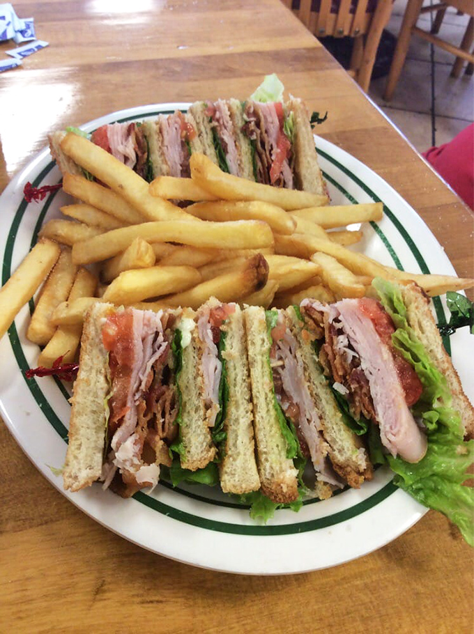 The club sandwich—diner royalty stacked three layers high. A testament to the timeless truth that everything tastes better with bacon and proper triangular cutting.