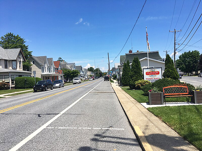 A sunny day along a quiet main street in Clayton, Delaware, featuring small-town homes, parked cars, and the Clayton Town Hall sign.