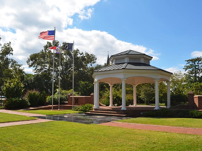 Classic white gazebo, lush landscaping, and proudly flying flags honoring the nation and its heroes. A serene tribute at the heart of this small Southern town.