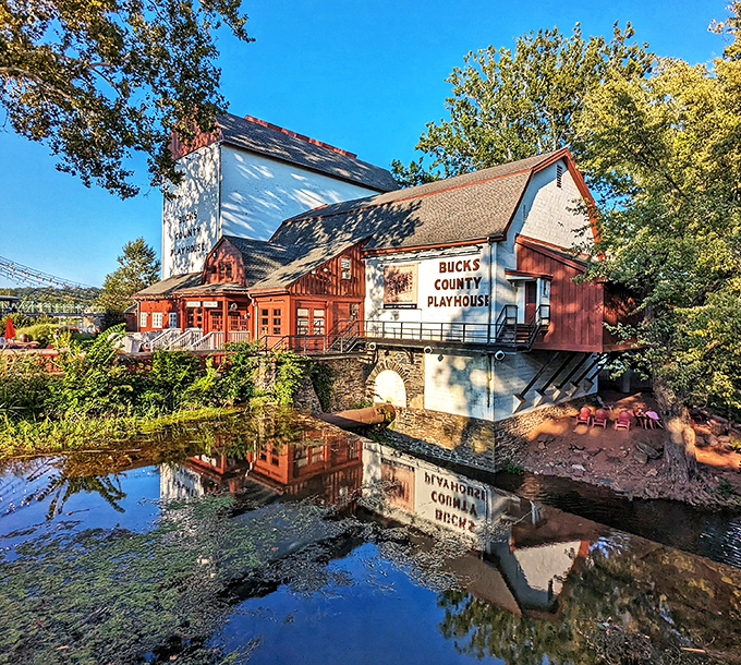 The historic playhouse reflects perfectly in still waters, doubling the magic of live theater.