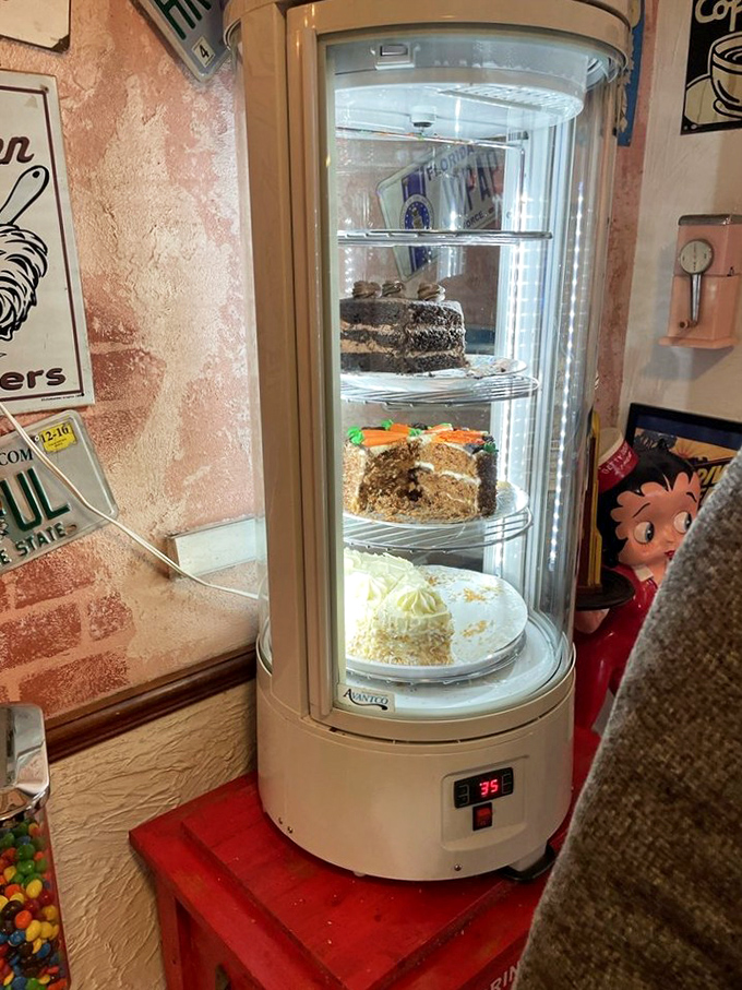 The rotating cake display—a glass tower of temptation that makes willpower crumble faster than the crust on that carrot cake.