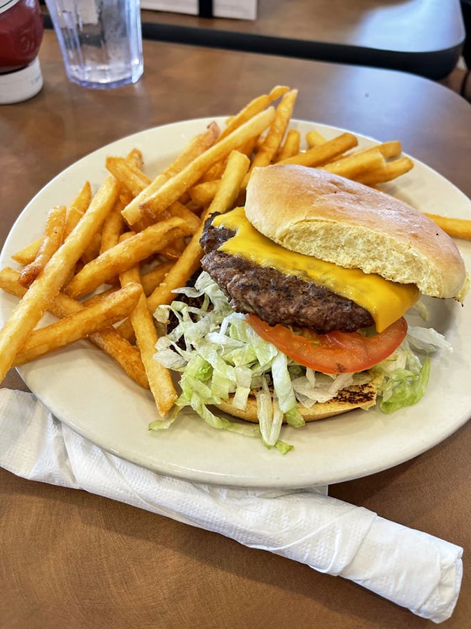 Behold the cheeseburger in its natural habitat—surrounded by golden fries and waiting patiently to fulfill its delicious destiny.