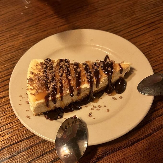This cheesecake with chocolate drizzle and toffee bits isn't just dessert—it's what happiness would look like if it took solid form.