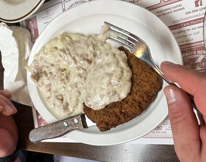 Chicken fried steak smothered in creamy gravy – a dish that transforms ordinary mornings into extraordinary comfort food experiences.