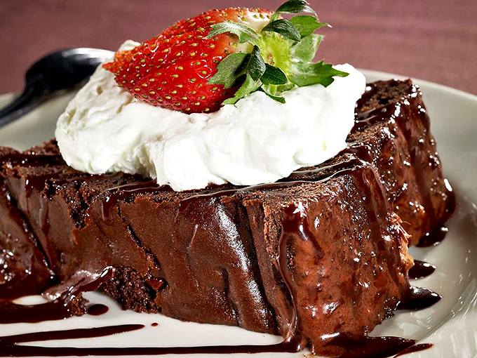 A chocolate cake so decadent it should require a warning label. That whipped cream and strawberry aren't garnishes—they're necessary palate refreshers between bites.