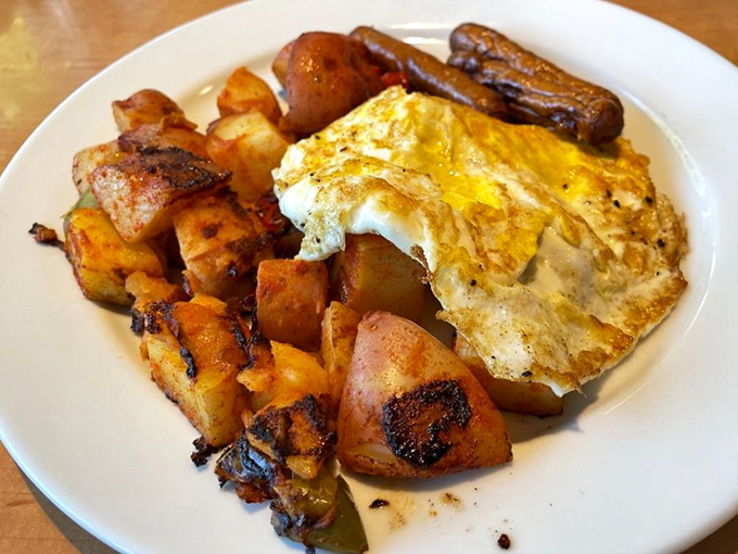 The holy trinity of breakfast: perfectly cooked eggs, crispy potatoes, and sausage. Morning salvation on a white plate. 