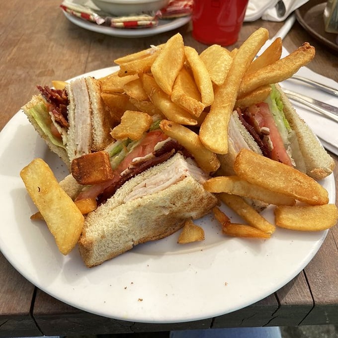 The club sandwich: three layers of bread engineering that has sustained American lunches since the Roaring Twenties. Those golden fries aren't just sides—they're co-stars.