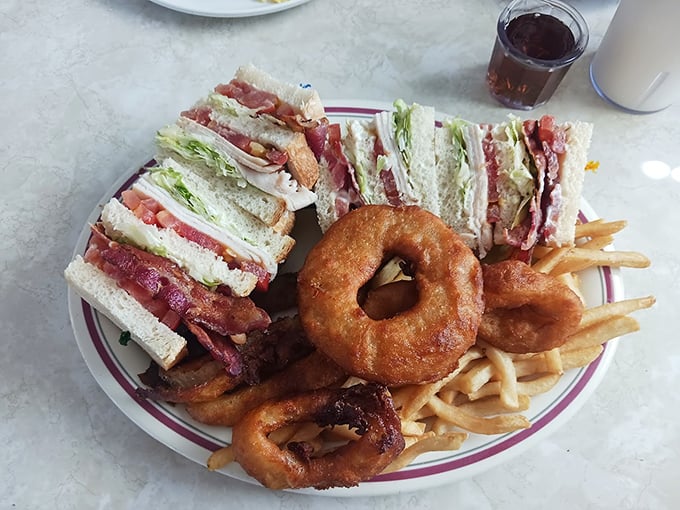 Club sandwich architecture that defies gravity, with onion rings that could double as golden halos for food angels.