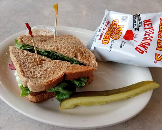 A sandwich that requires both hands and several napkins—the universal sign of something worth eating. Served with a pickle that's more than just a garnish.