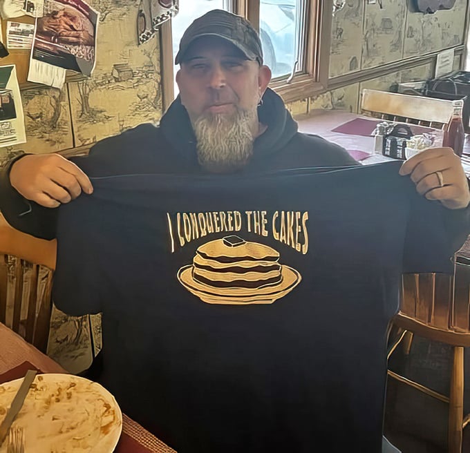 The "I Conquered The Cakes" shirt is the local equivalent of summiting Everest—a badge of honor for those brave enough to tackle their legendary pancake challenge.
