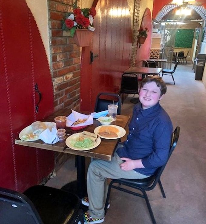 A young diner grins at his feast—proof that appreciating good Mexican food is a skill best learned early in life.