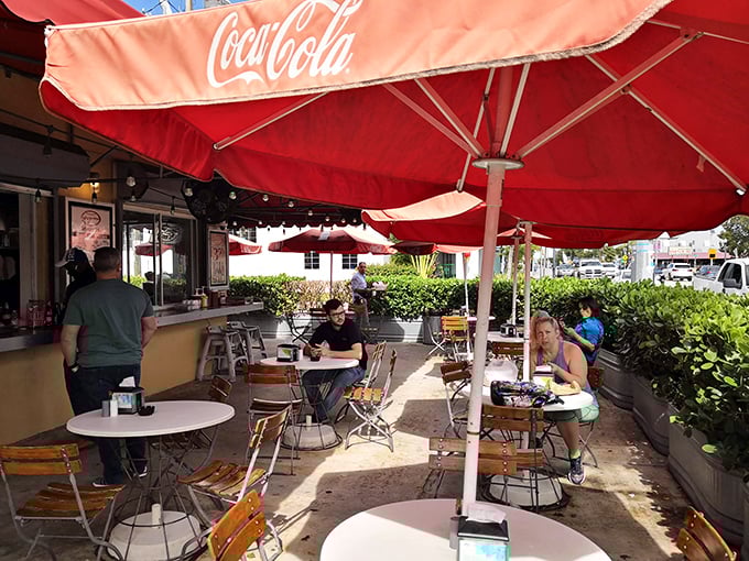 The lunch crowd knows what's up – Coca-Cola umbrellas providing shade for serious hot dog appreciation sessions.