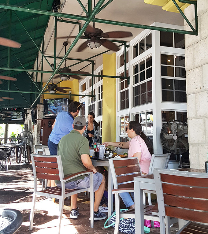 The covered patio offers prime people-watching real estate while ceiling fans create that perfect breeze that somehow never disturbs your napkin. 