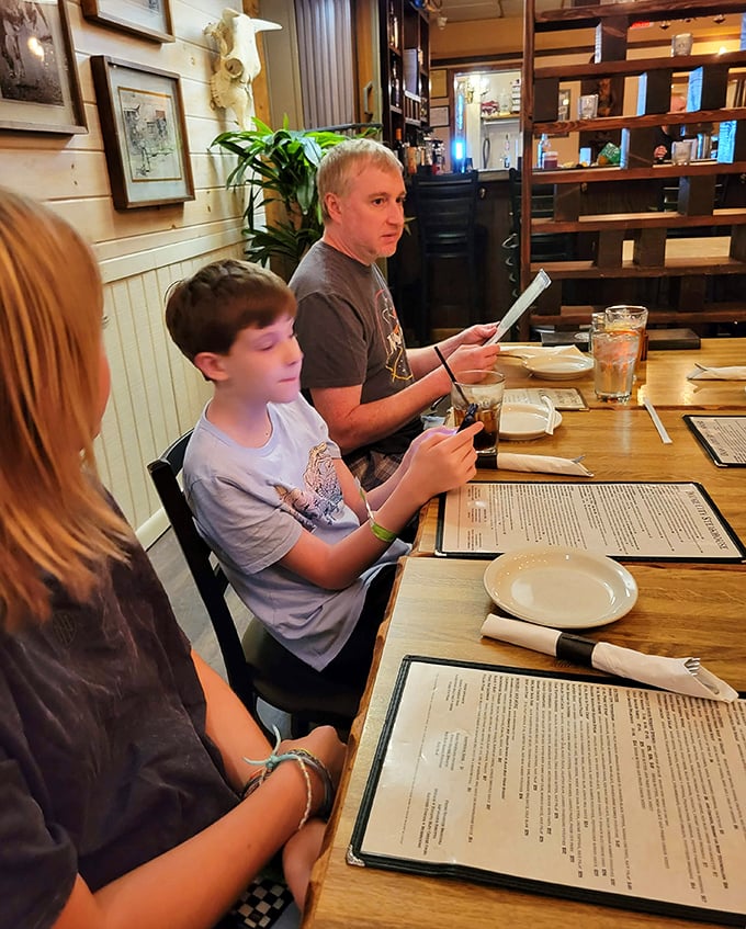 Family dining as it should be—menus big enough to hide behind while deciding whether to splurge on the bone-in ribeye. Spoiler alert: always yes.