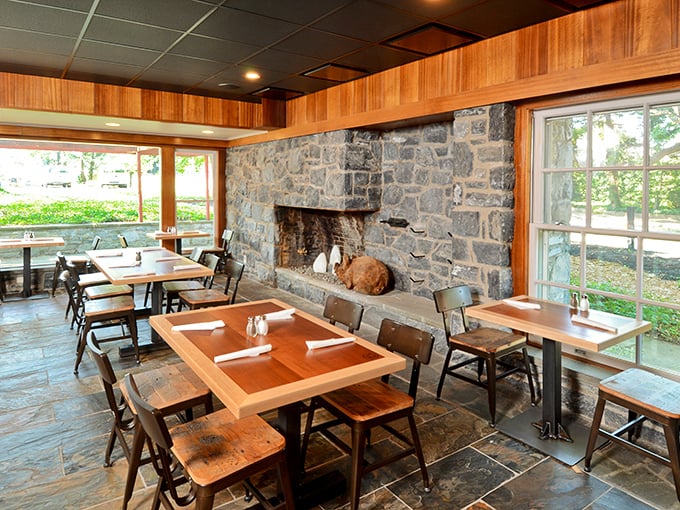Stone walls, wooden tables, and natural light create a dining space that feels both rustic and refined—like a barn that went to finishing school.
