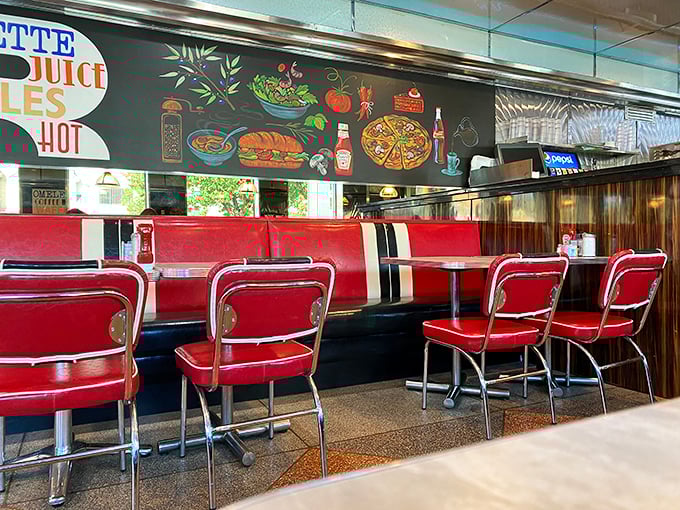 Red booths against colorful wall art—the classic diner equation where comfort meets character, and every table holds the promise of satisfaction.