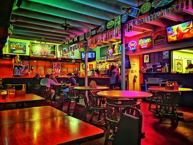As evening falls, the bar transforms into a neon-lit wonderland where cold beers, hot food, and good conversation flow in equal measure.