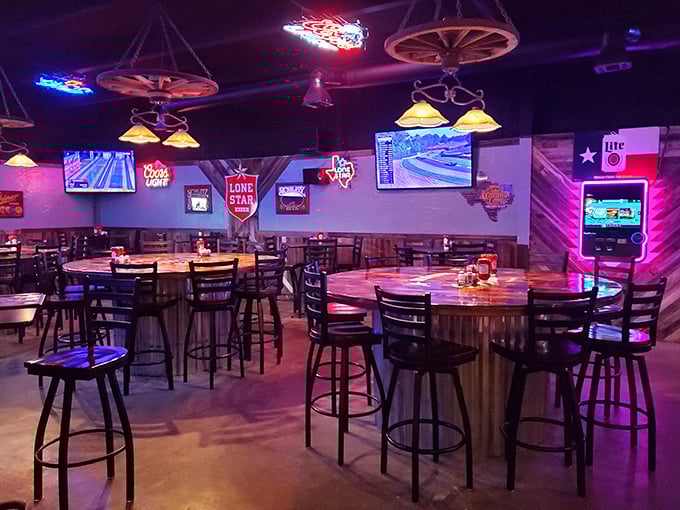 The bar area combines Texas nostalgia with modern comforts—wagon wheels hanging from the ceiling while sports play on flat-screens.