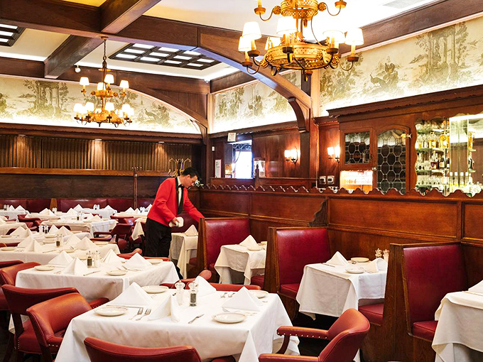 The dining room feels like a private club where everyone's a member, with servers in red jackets moving through the space like choreographed dancers.