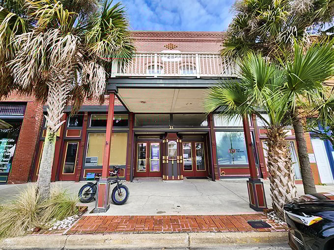 The Dixie Theatre's façade hints at entertainment treasures within—a cultural oasis where palm trees stand guard at the entrance.