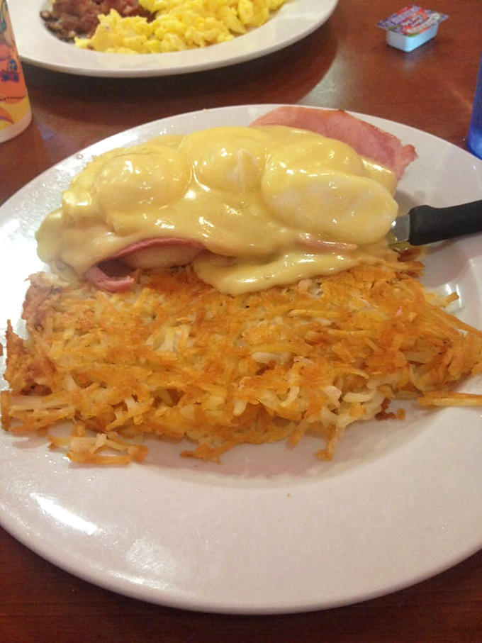 Hash browns crisped to golden perfection, crowned with ham and hollandaise – breakfast architecture that would make Frank Lloyd Wright order seconds.