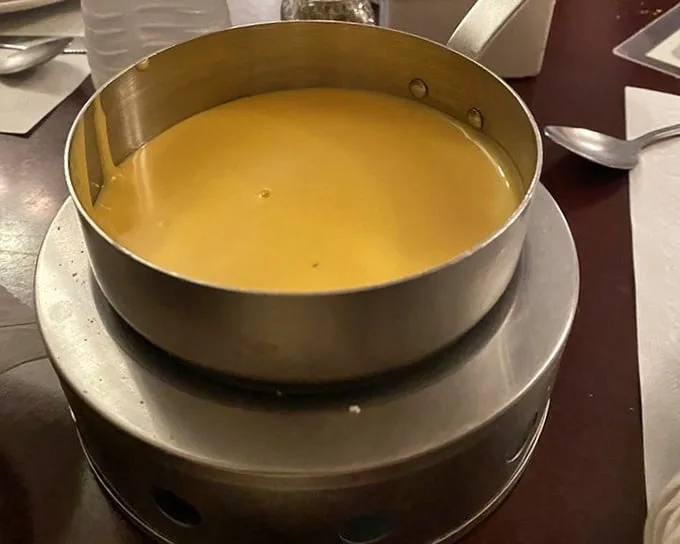 The fondue arrives like liquid gold in its metal chalice—a communal pot of joy waiting to transform ordinary bread into extraordinary memories.