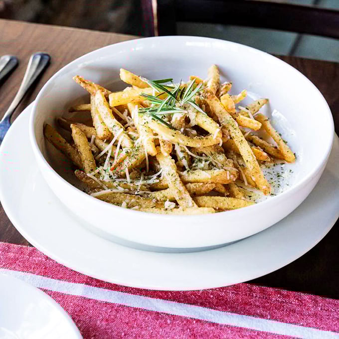 These aren't just fries—they're golden wands of potato magic, dusted with herbs and parmesan that transform the humble spud into something extraordinary.