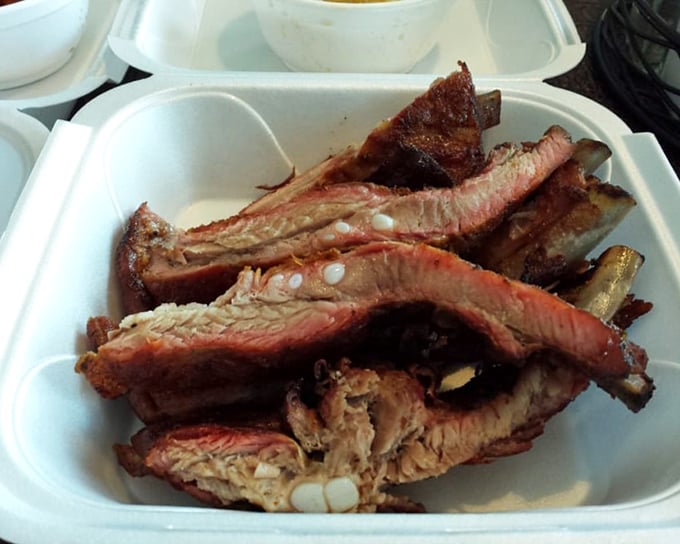 Ribs with that perfect pink smoke ring that BBQ aficionados chase like treasure hunters. The meat isn't falling off the bone—it's respectfully departing.