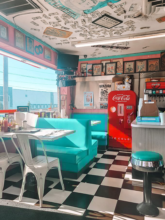The vintage Coca-Cola machine stands sentinel in the corner, a fizzy red guardian watching over turquoise booths and checkered dreams.