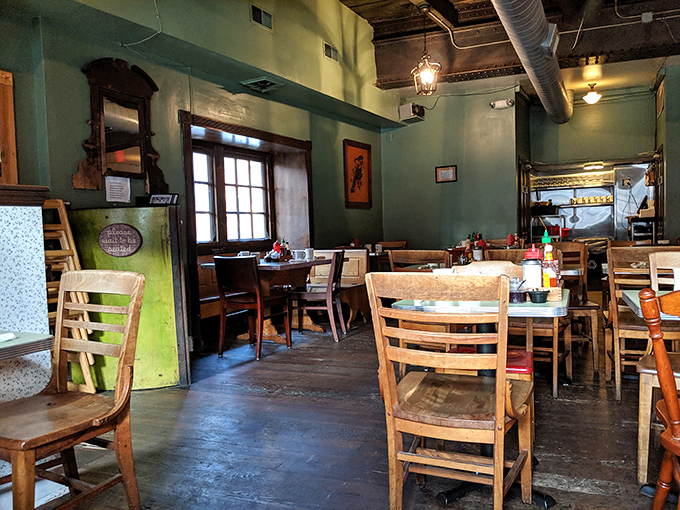 The dining room feels like your coolest friend's living room – sage green walls, wooden tables, and windows that frame the day like perfect Polaroids.