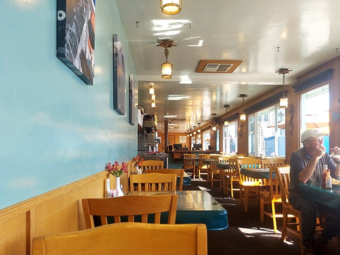 Sunlight streams through windows illuminating wooden chairs and aqua walls—the dining room equivalent of that perfect beach day you never want to end.