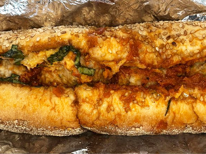 A proper cheesesteak in its natural habitat—wrapped in foil, ready to be devoured alongside crispy fries and an ice-cold soda.