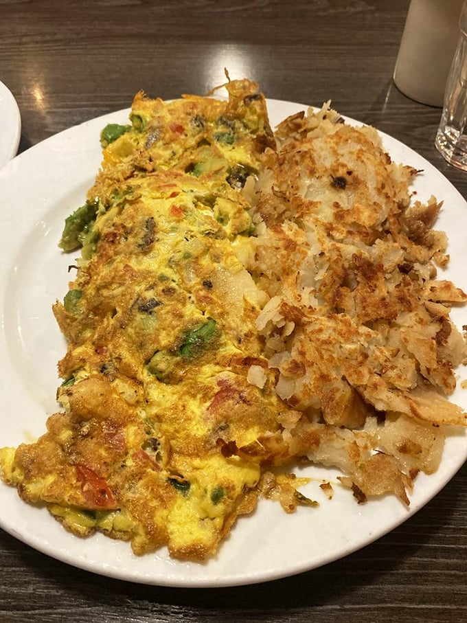 An omelet that's clearly been to culinary finishing school—perfectly folded, generously filled, and paired with hash browns crisped to golden perfection.