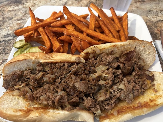 A proper cheesesteak with a mountain of seasoned meat and those golden fries—the kind of lunch that necessitates loosening your belt afterward.