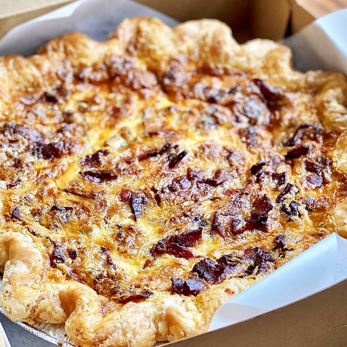 A quiche Lorraine that would make Julia Child slow-clap in approval—golden, puffy, and studded with bacon like stars in a savory night sky.