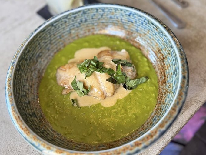 A vibrant green sea of pea purée cradles perfectly sautéed fish—like Neptune himself designed a color-coordinated seafood masterpiece.