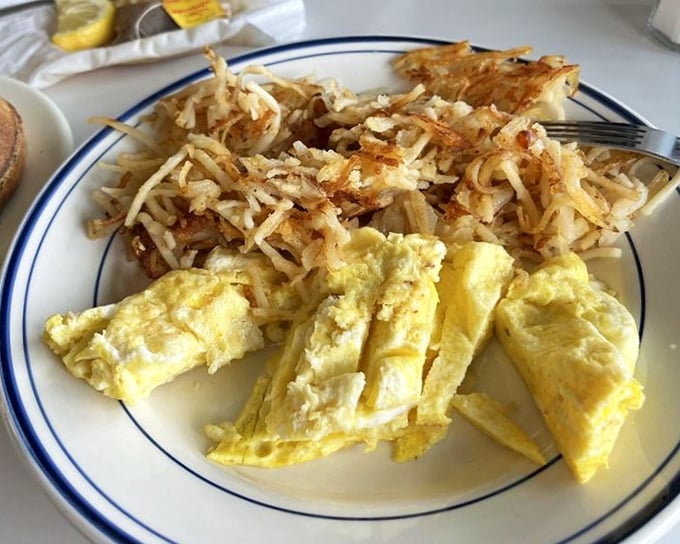 Scrambled eggs done right – actually fluffy, not just chopped up and abandoned. Paired with hash browns that crackle with each forkful of potato perfection.