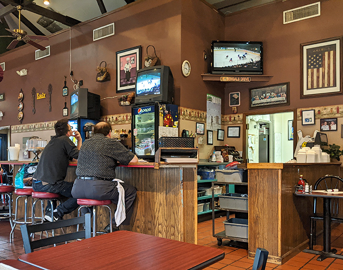 The counter seating area—where solo diners become temporary family and the American flag watches over breakfast negotiations with patriotic approval.