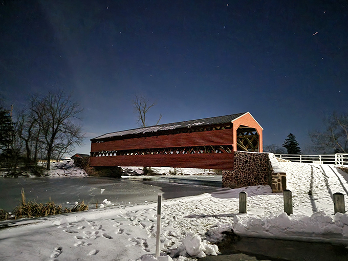 Under starlight, the bridge transforms into something magical—a crimson silhouette against the winter night that would make Norman Rockwell reach for his brushes.