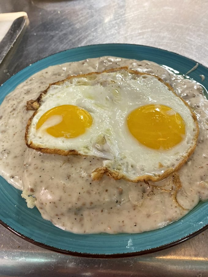 Breakfast that doesn't care about your diet plans. Two sunny eggs nestled in creamy gravy—the morning equivalent of a warm hug from your favorite aunt.